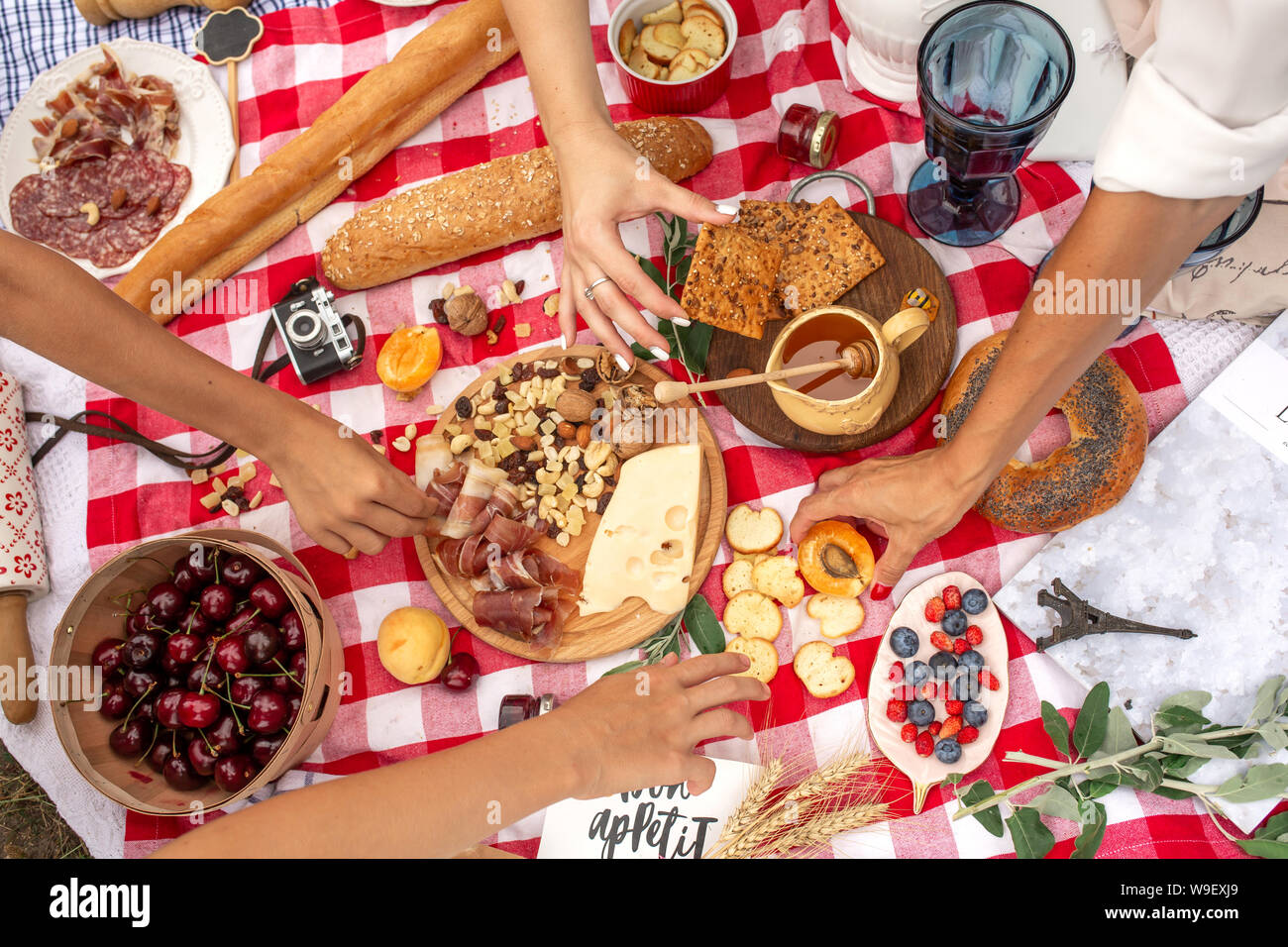 Top view people take food from checkered picnic blanket. Outdoor summer ...