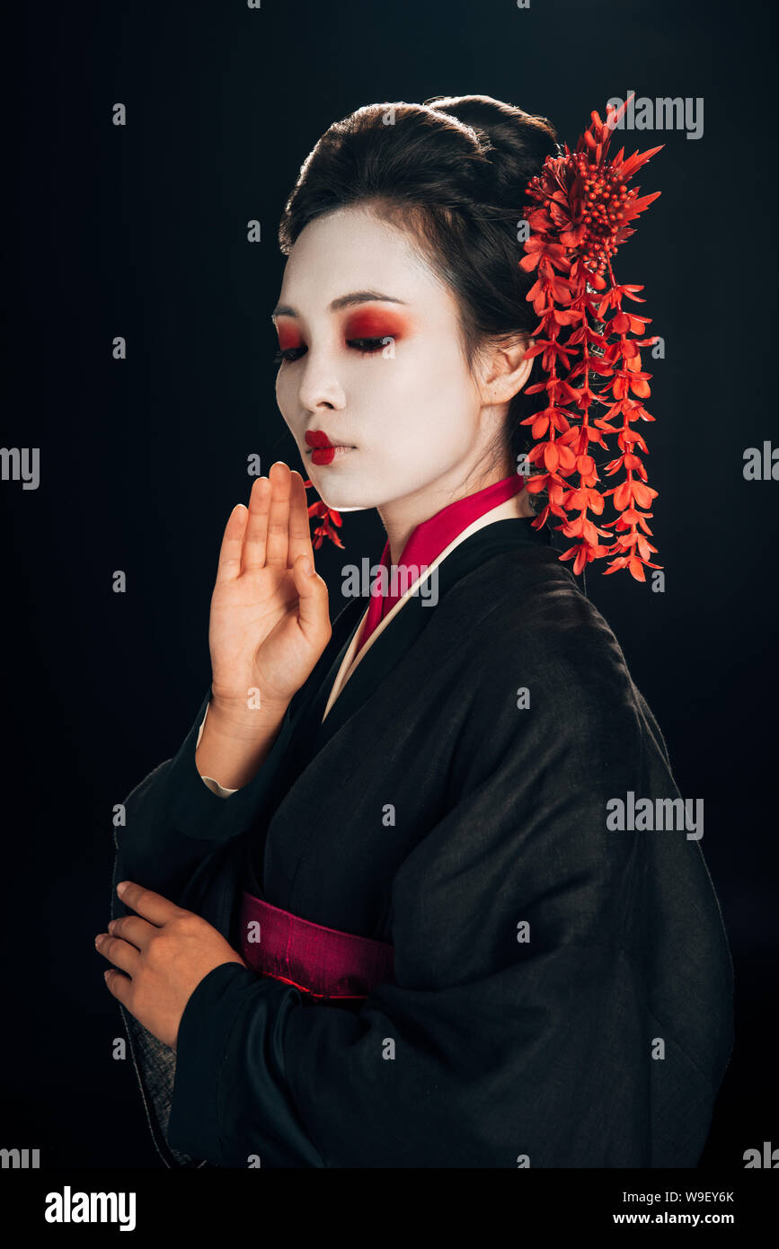 beautiful geisha in black and red kimono and flowers in hair with hand ...