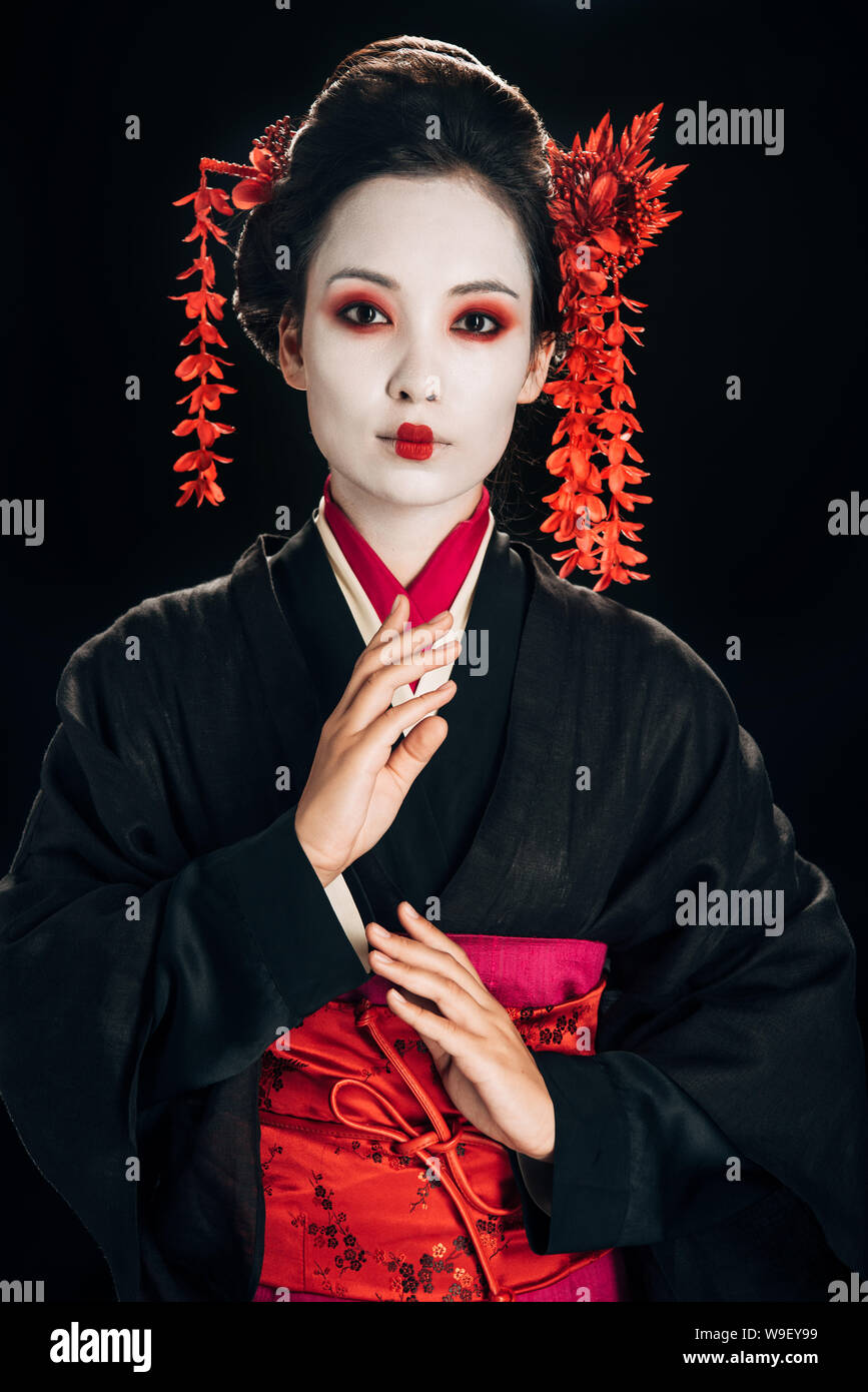 beautiful geisha in black and red kimono gesturing isolated on black ...