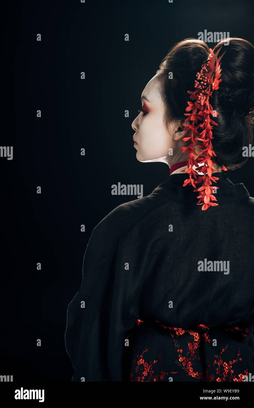 back view of beautiful geisha in black and red kimono and flowers in ...