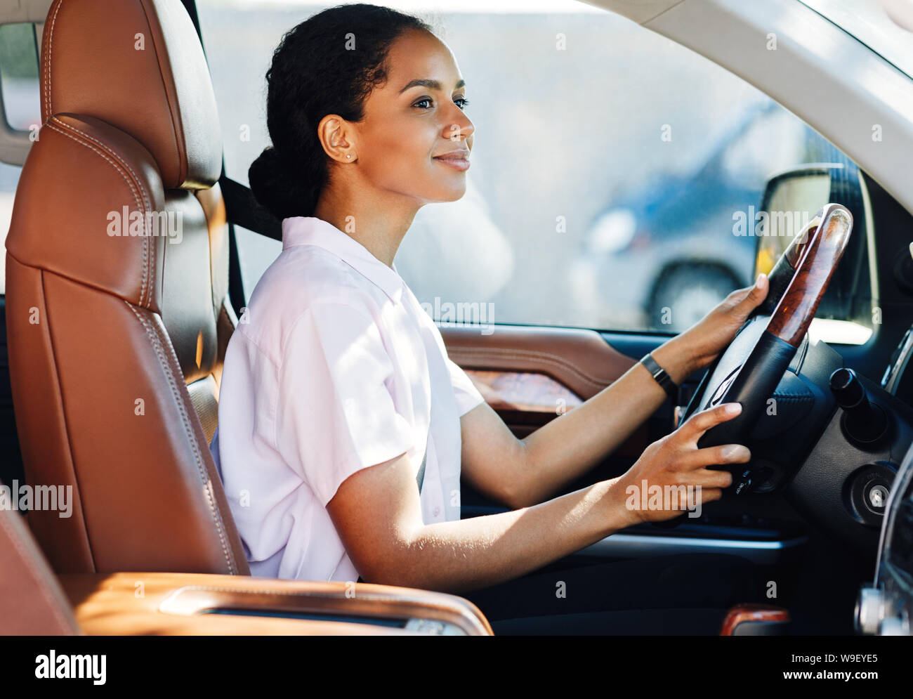 Confident young woman driving car. Side view of female holding a ...