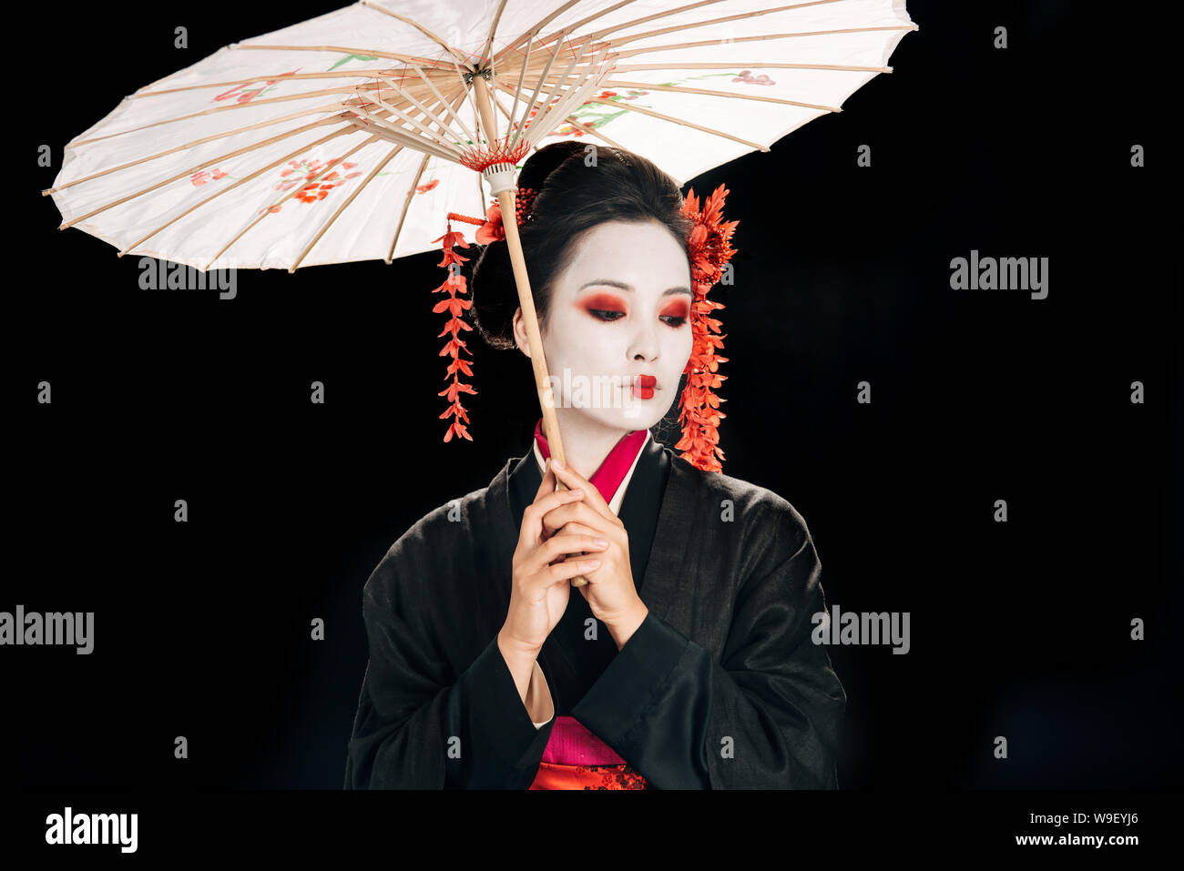 beautiful geisha in black kimono with red flowers in hair holding ...
