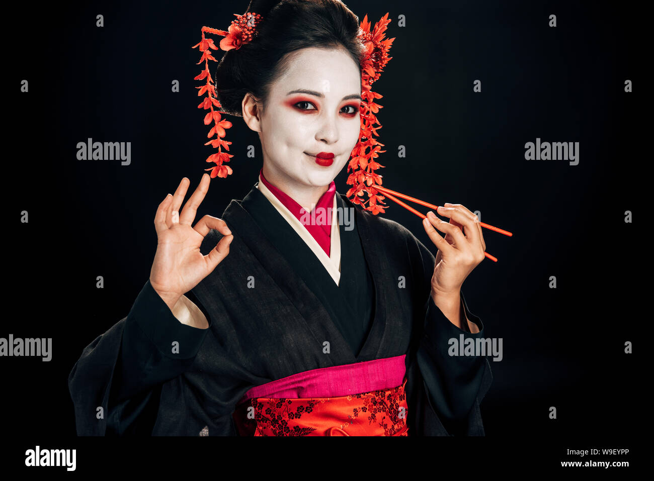 smiling beautiful geisha in black kimono with red flowers in hair ...