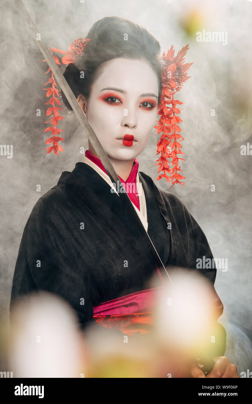 selective focus of beautiful geisha in black kimono holding katana in ...