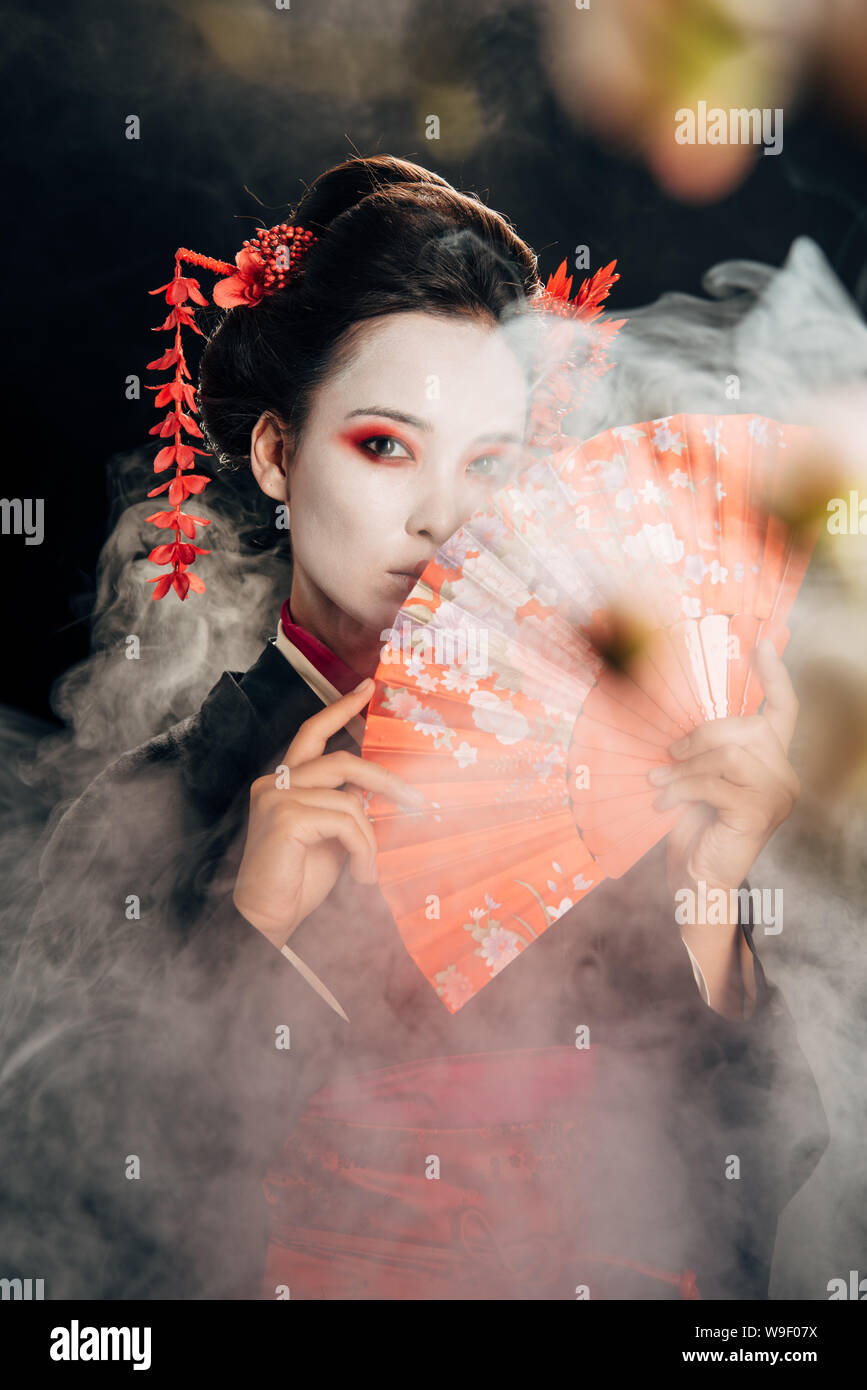 selective focus of beautiful geisha in black kimono with flowers in ...