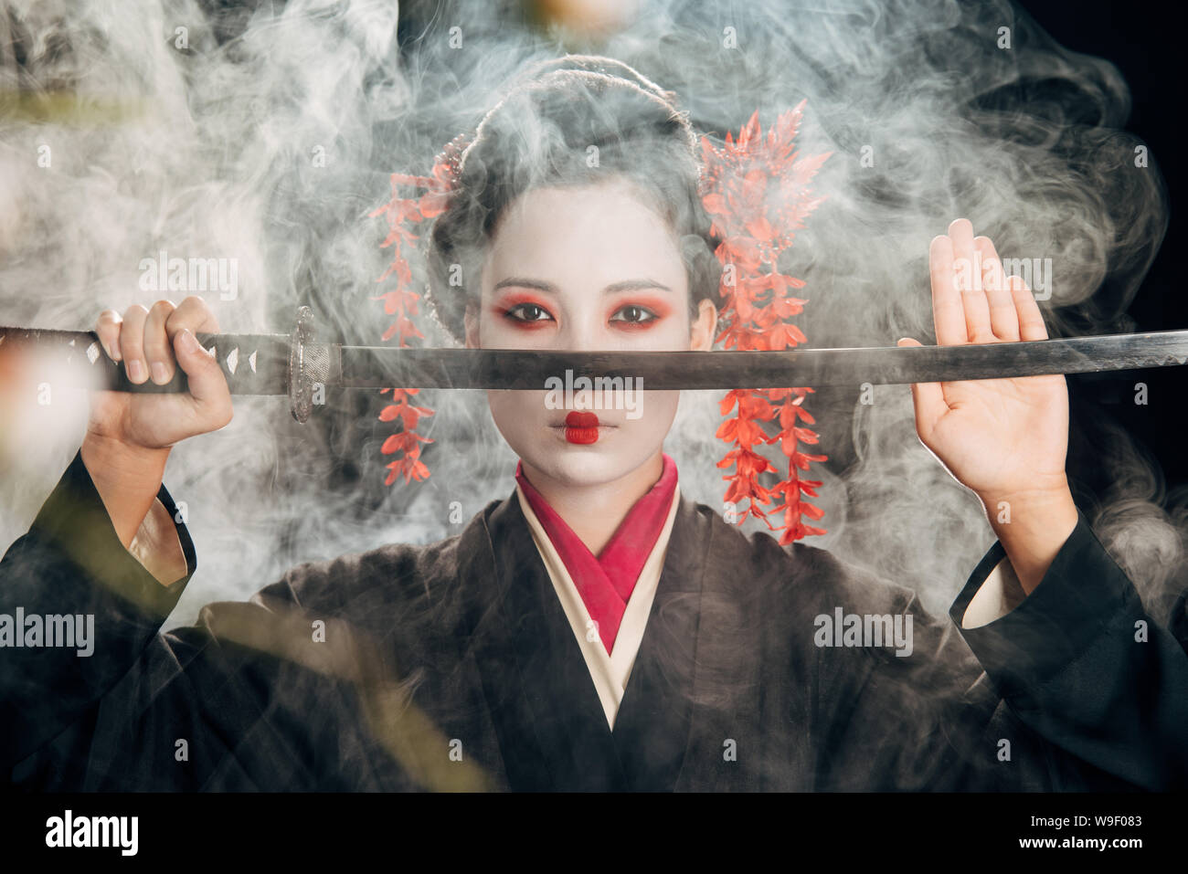 selective focus of geisha in kimono holding katana in smoke and sakura ...