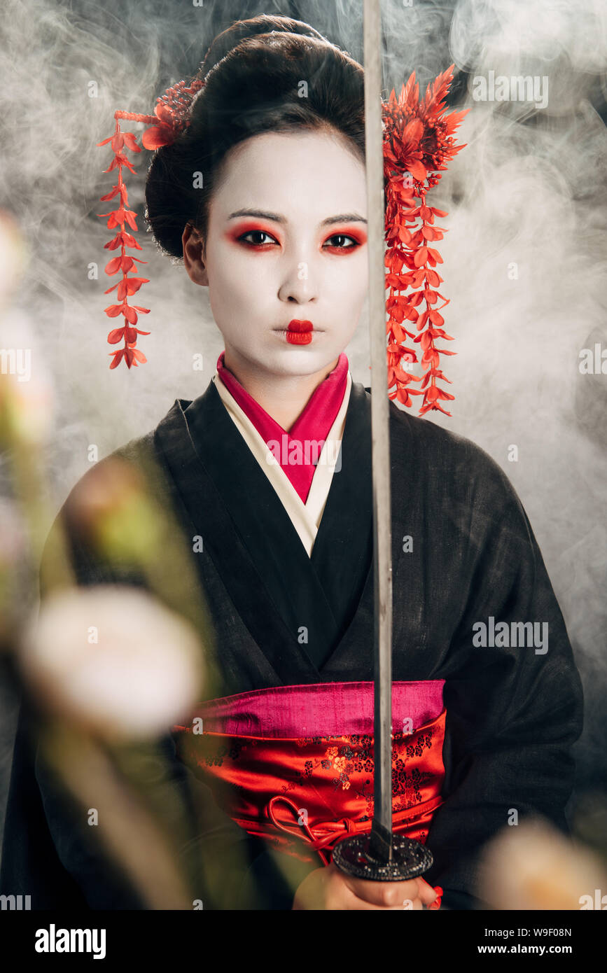 selective focus of beautiful geisha in black kimono holding katana in ...