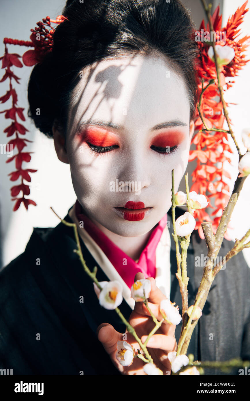 sakura branches and beautiful geisha with red and white makeup in ...