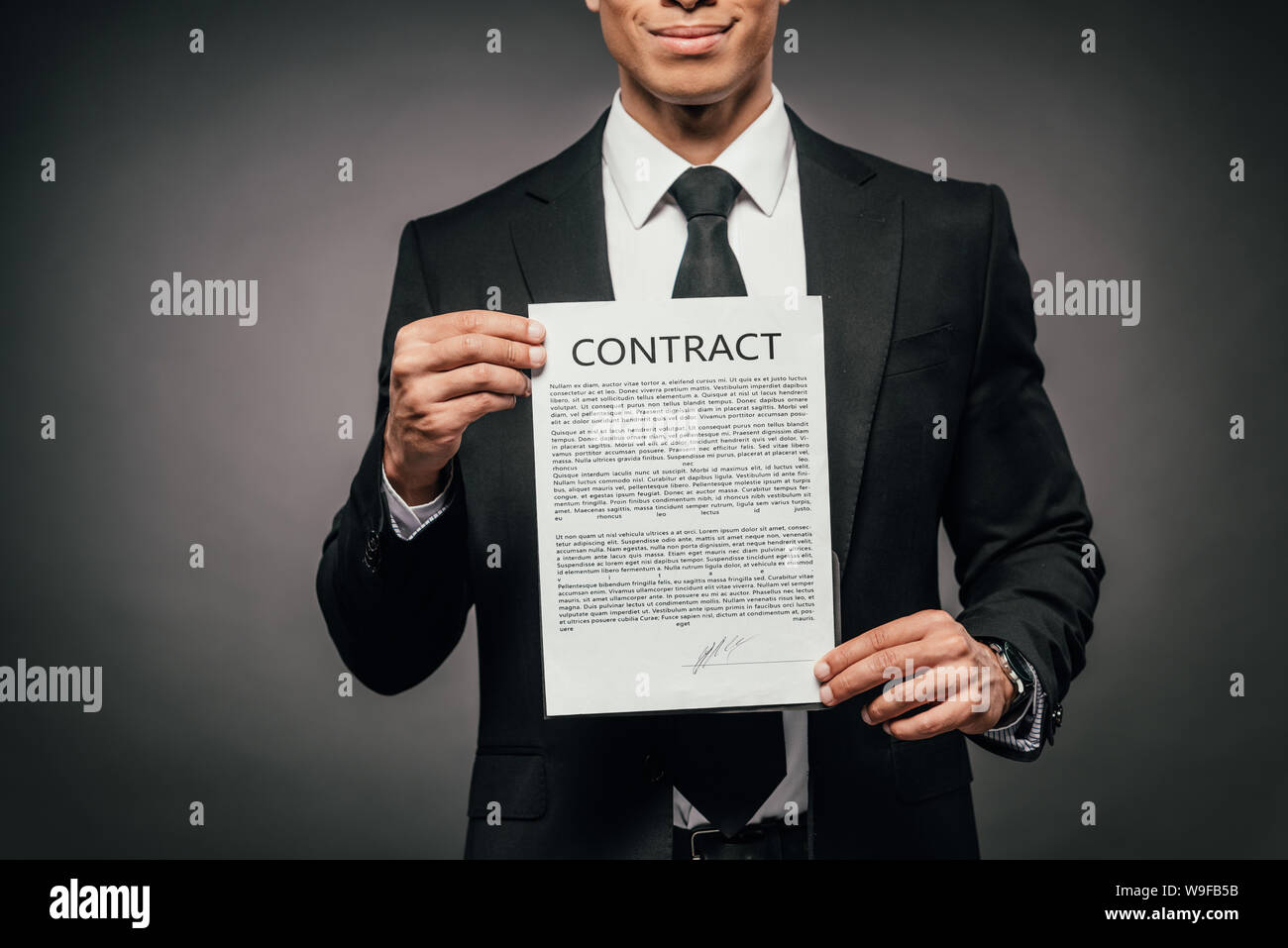 partial view of cheerful african american businessman showing contract ...