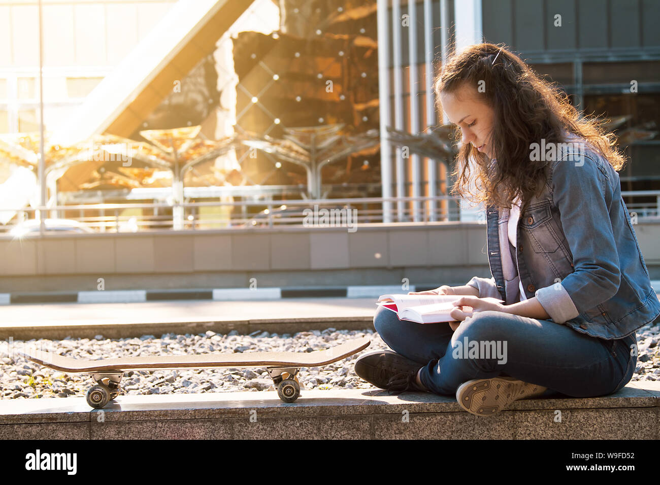schoolgirl reading a book on a street in sunlight Stock Photo - Alamy