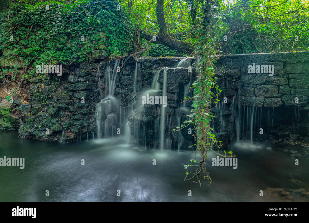 Stream flowing over disused water works Stock Photo - Alamy