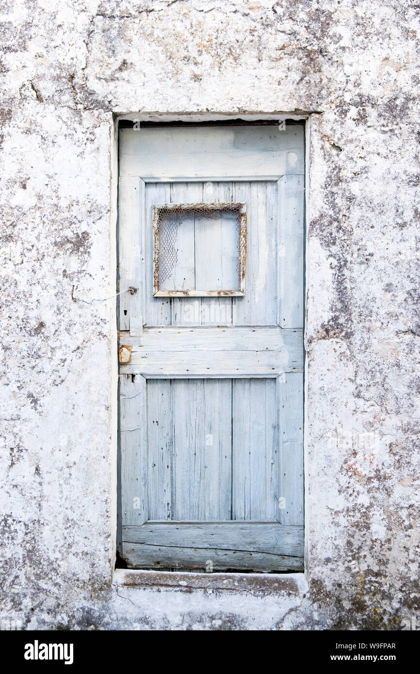 A pale blue wooden door set in a crumbling facade in the abandoned ...