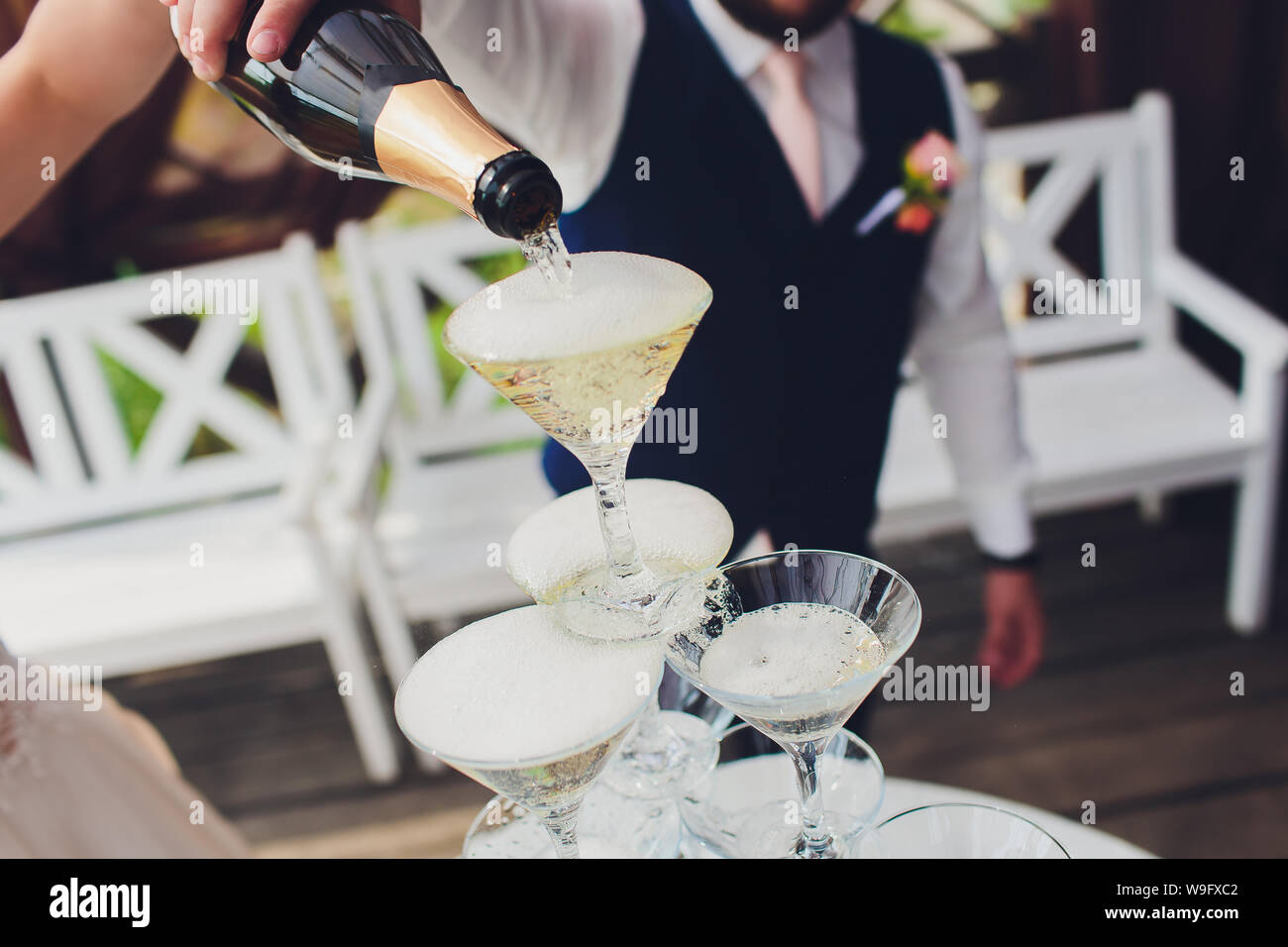 Pyramid of wine glasses with champagne . Champagne is poured into the ...