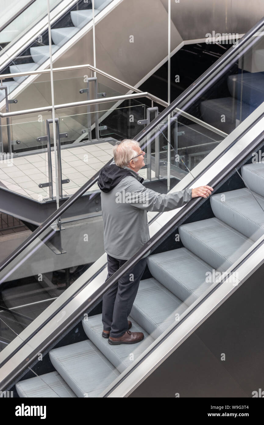 A Middle aged man riding an escalator alone Stock Photo - Alamy