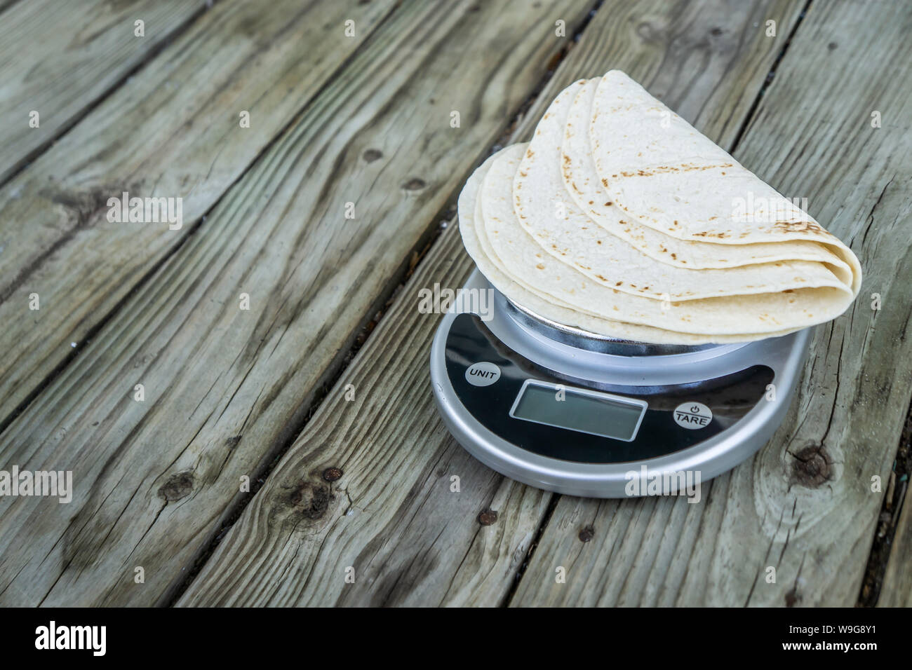 Low carb tortillas on a scale on wooden background - blank empty room ...