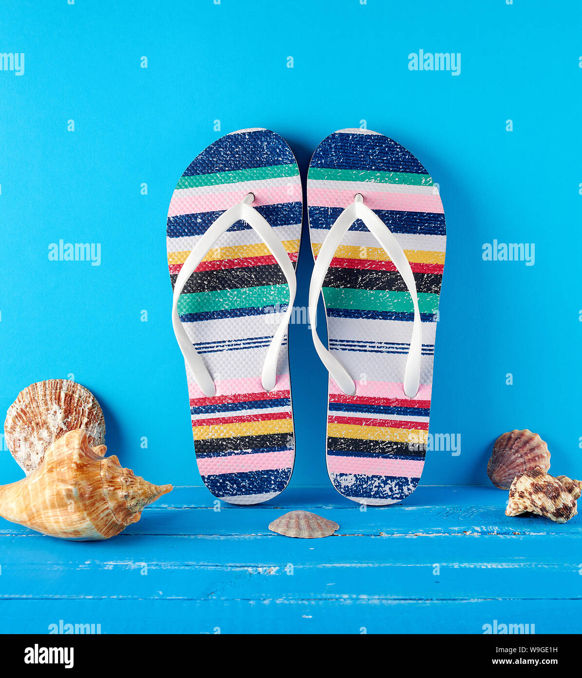 pair of multi-colored rubber slippers on a blue background, near ...