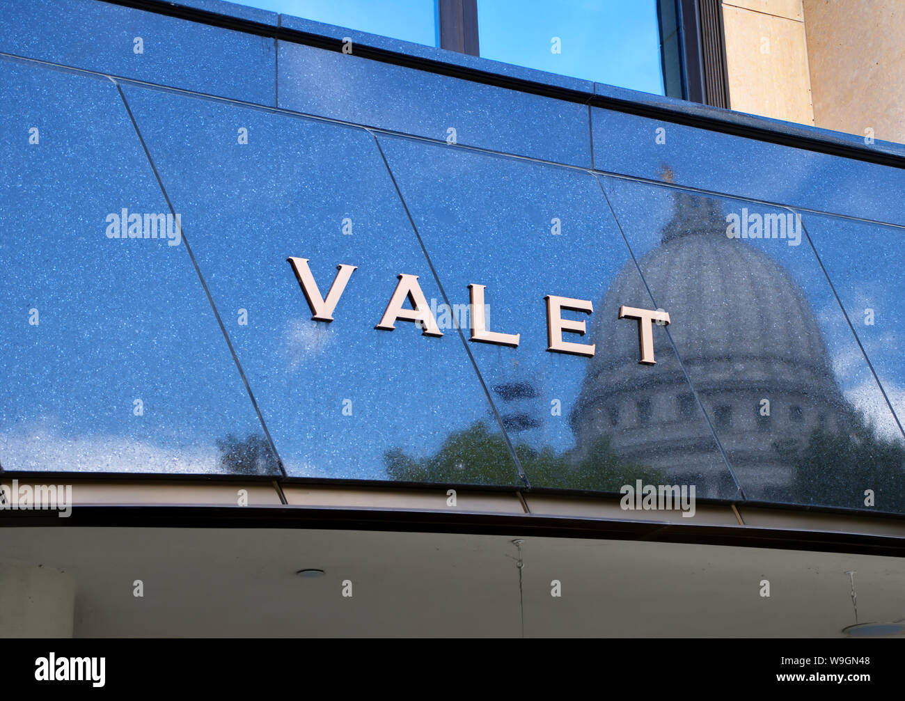 Raised letters valet sign on marble siding with a reflection of the ...
