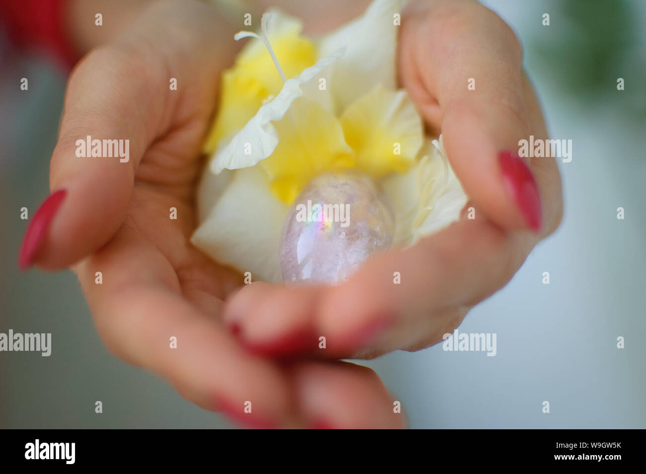 Indoors photo of female hand holding a yoni egg and white and yellow ...
