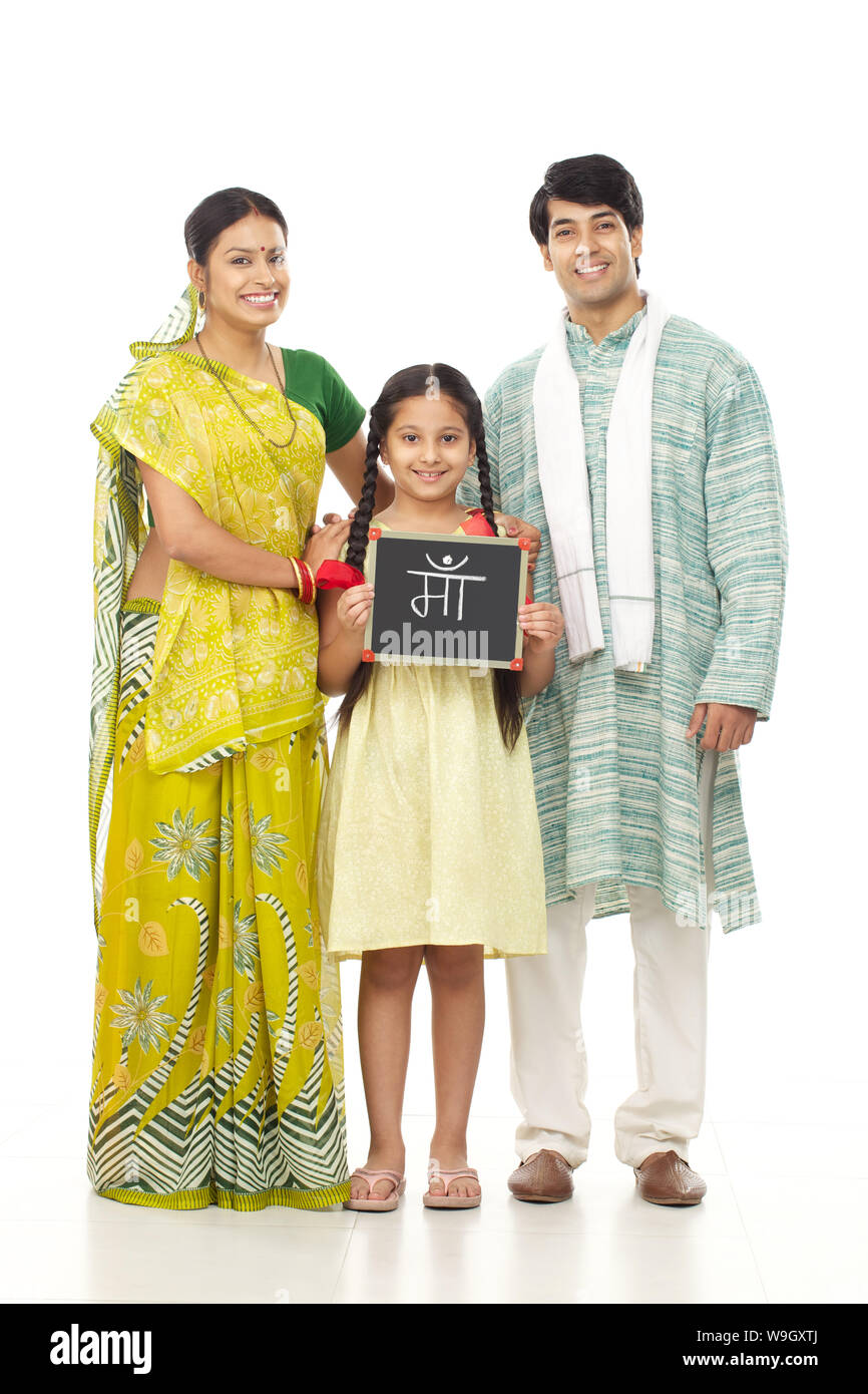 Girl holding a slate "maa" written on it standing with her parents ...
