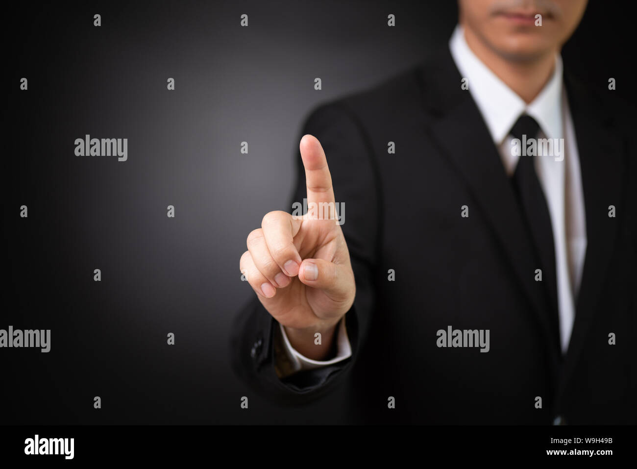 Businessman pointing with his finger against black background. Business ...