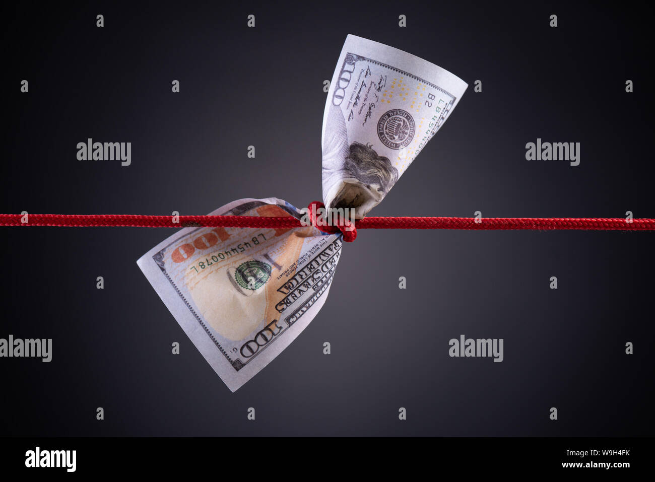 American dollar tied up in red rope knot on dark background with copy ...