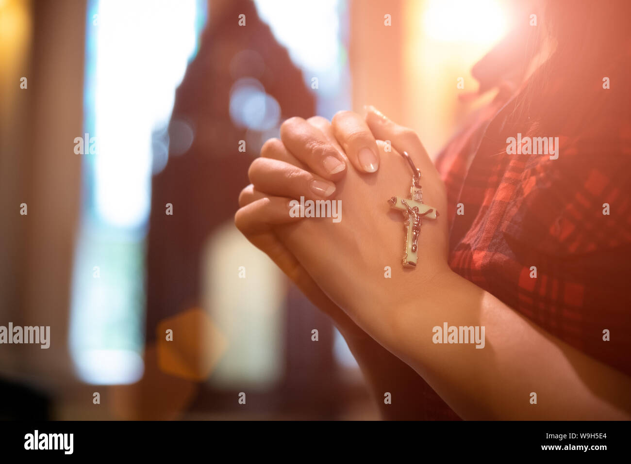 Woman hand holding rosary against cross and praying to God at church ...