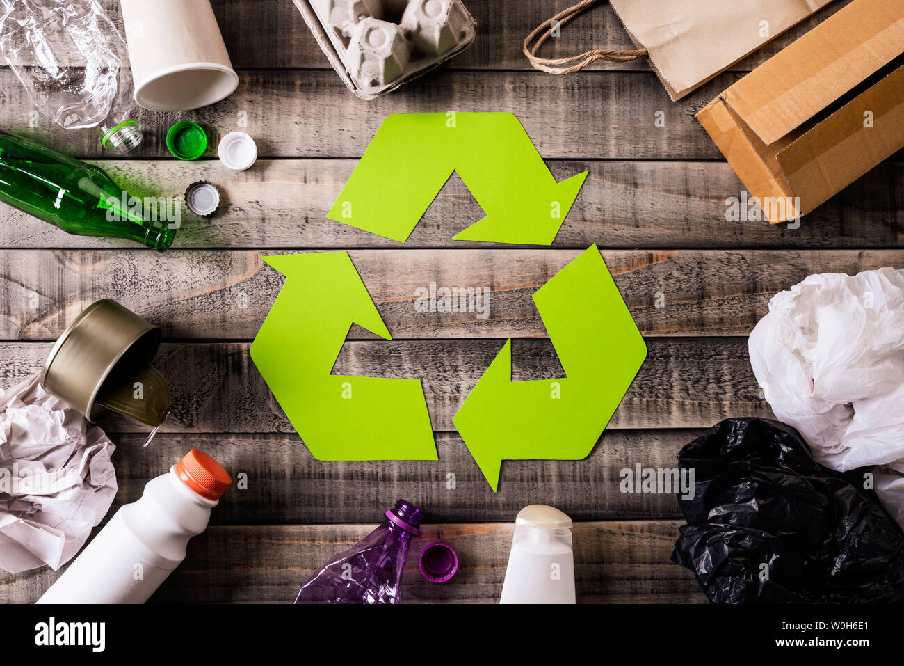 Top view of Different garbage materials with recycling symbol on table ...