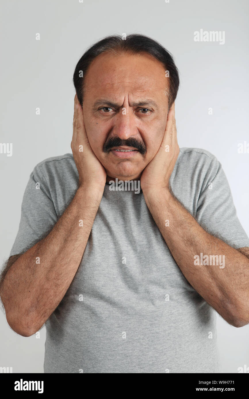 Mature man covering ears with hands Stock Photo - Alamy