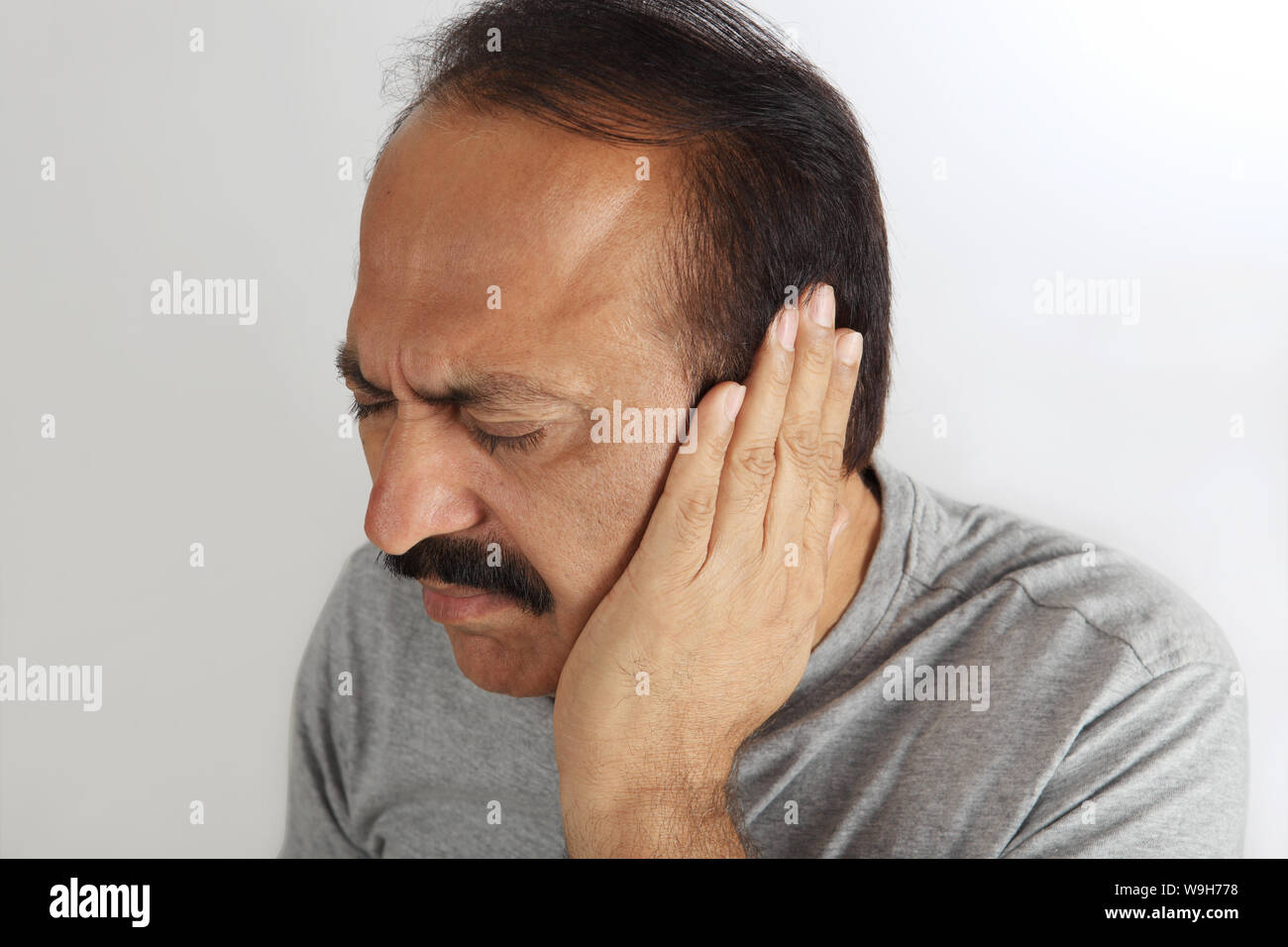 Mature man covering ears with hands Stock Photo - Alamy