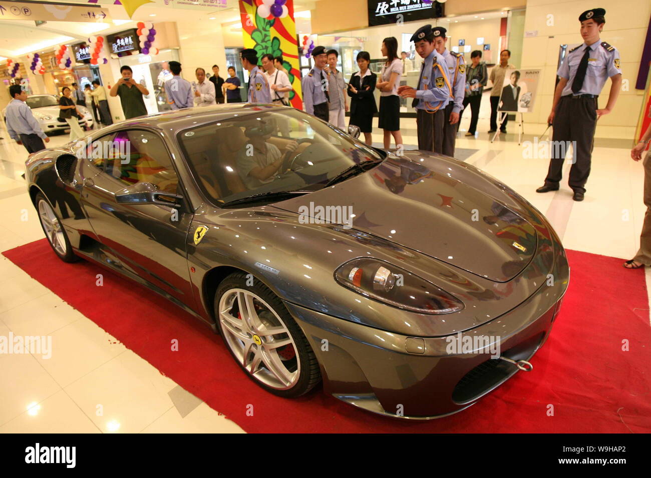 Chinese visitors view a Ferrari F430 displayed at a shopping mall in ...