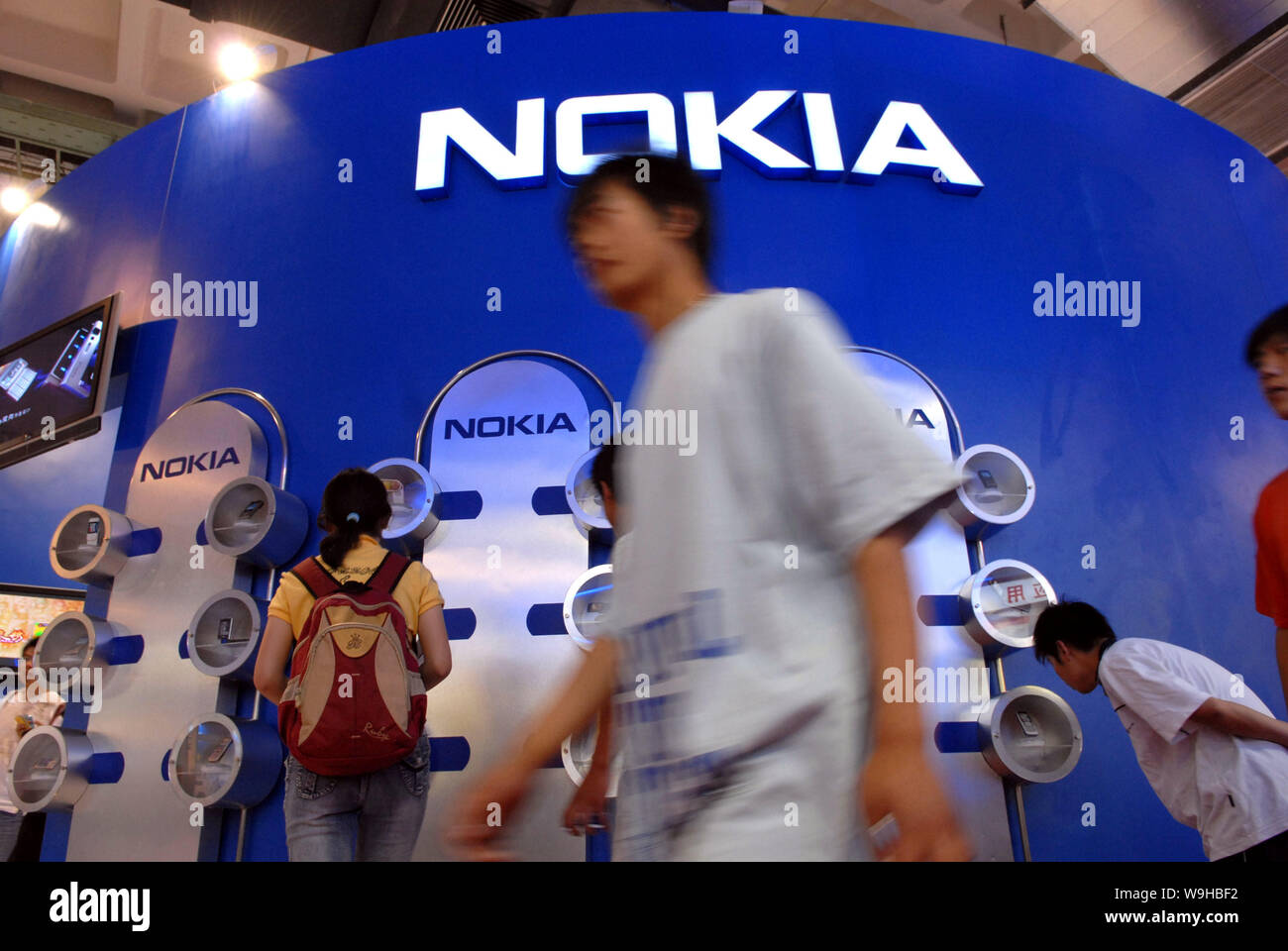 Chinese visitors walk through the stand of Nokia during an expo in ...
