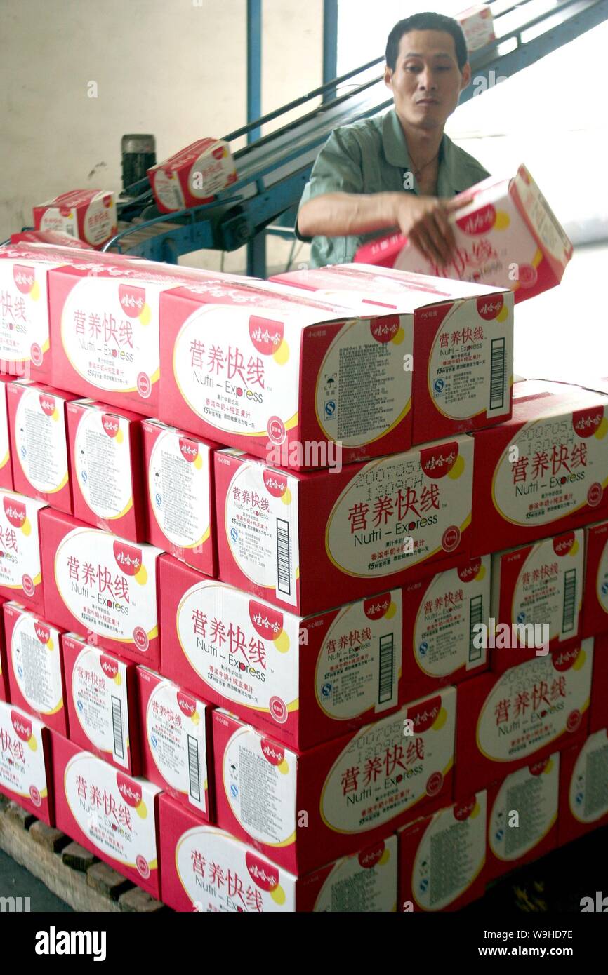 A Chinese factory worker piles boxes of Wahaha Nutri-Express drink on ...