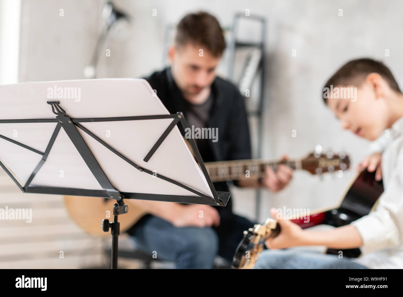 Music sheet standing in front of teacher and his young student playing ...