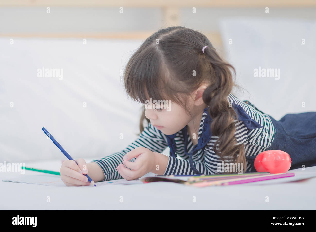 Cute asian little girl doing homework,writing with colourful pencils on ...