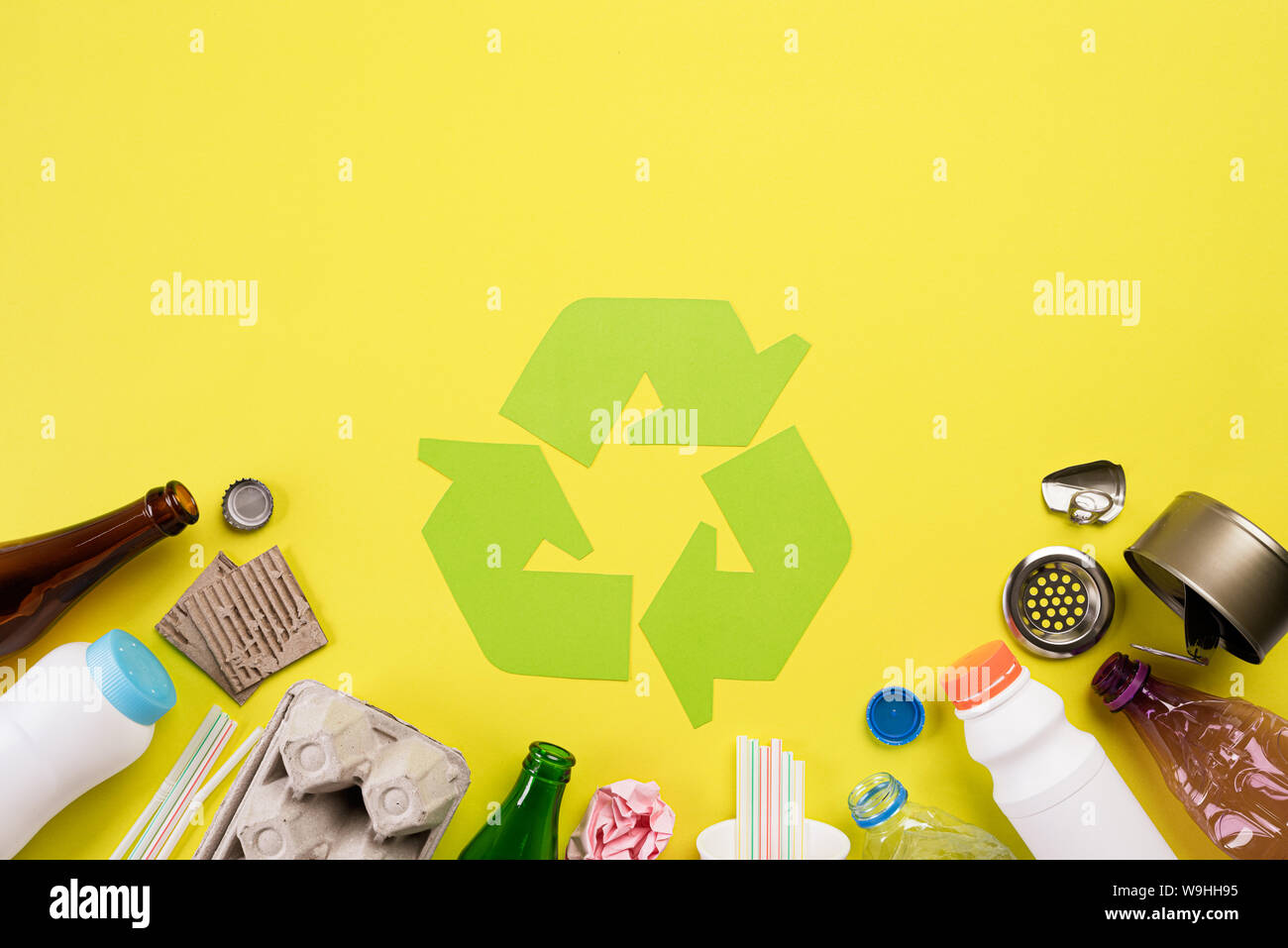 Top view of Different garbage materials with recycling symbol on yellow ...