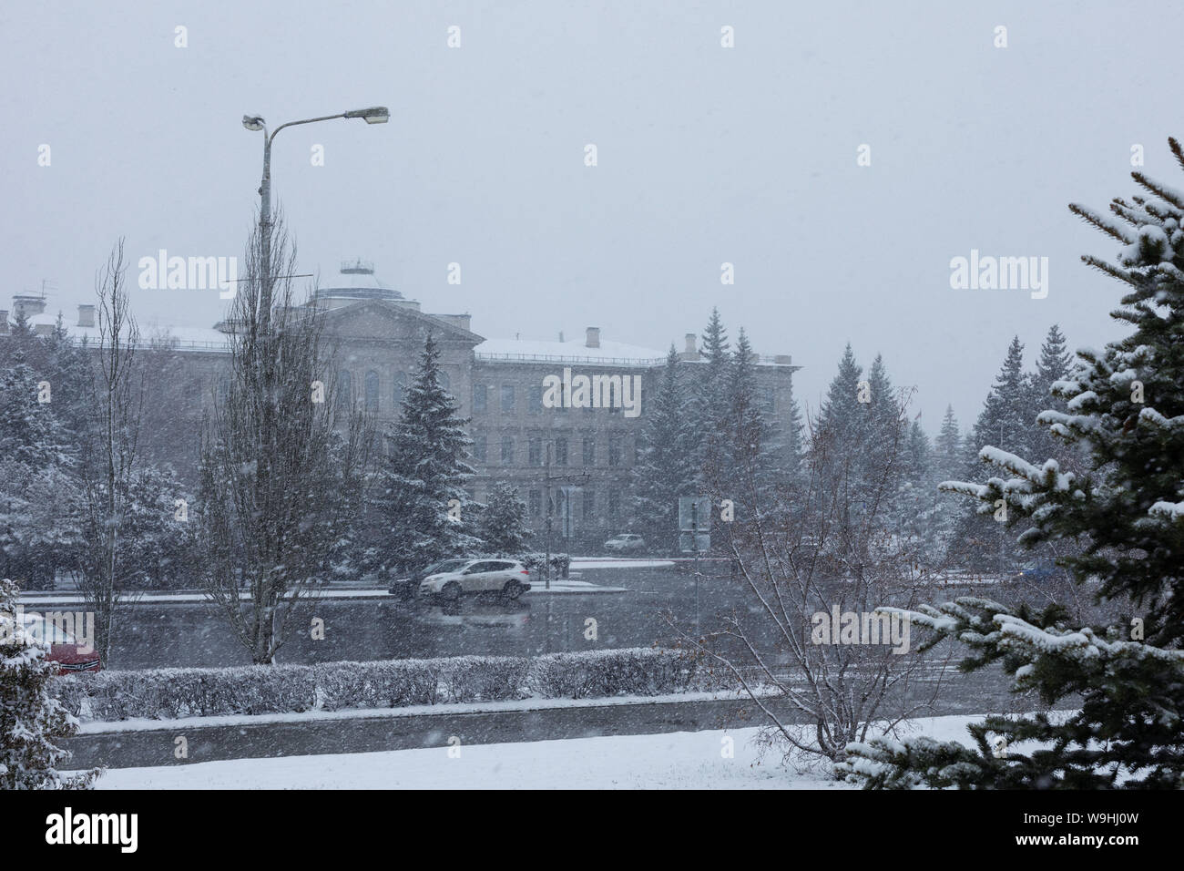 It is snowing, a city street with traffic and cars. urban winter ...