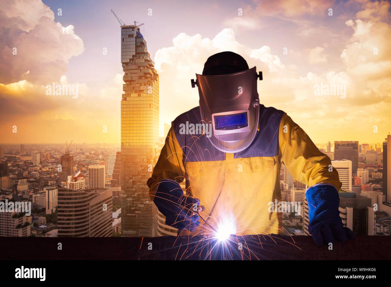 Welding worker welding steel structure with modern building in big city ...