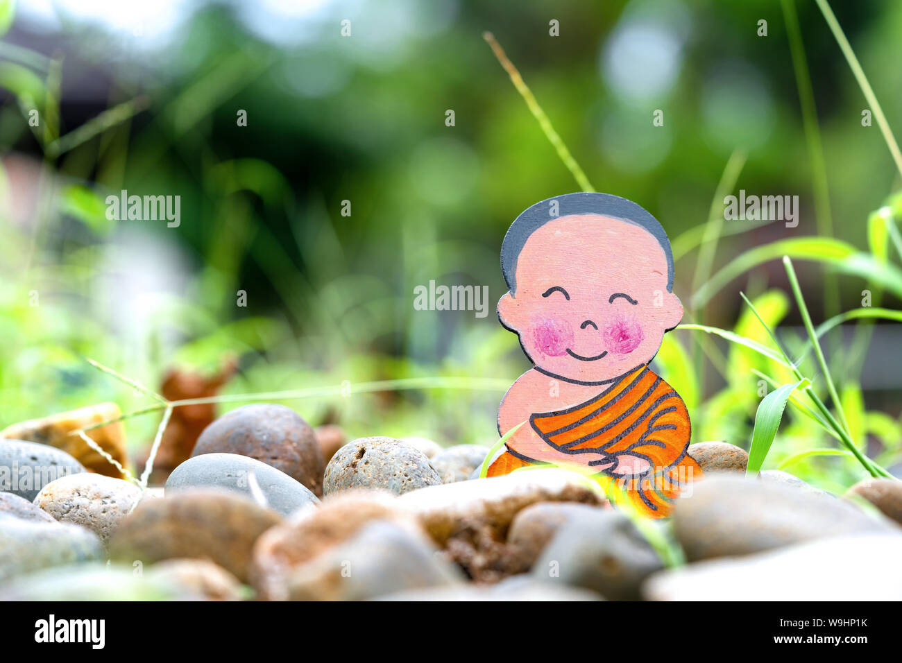 Little boy Buddhist, little Buddha, sitting on the sand on stones and ...