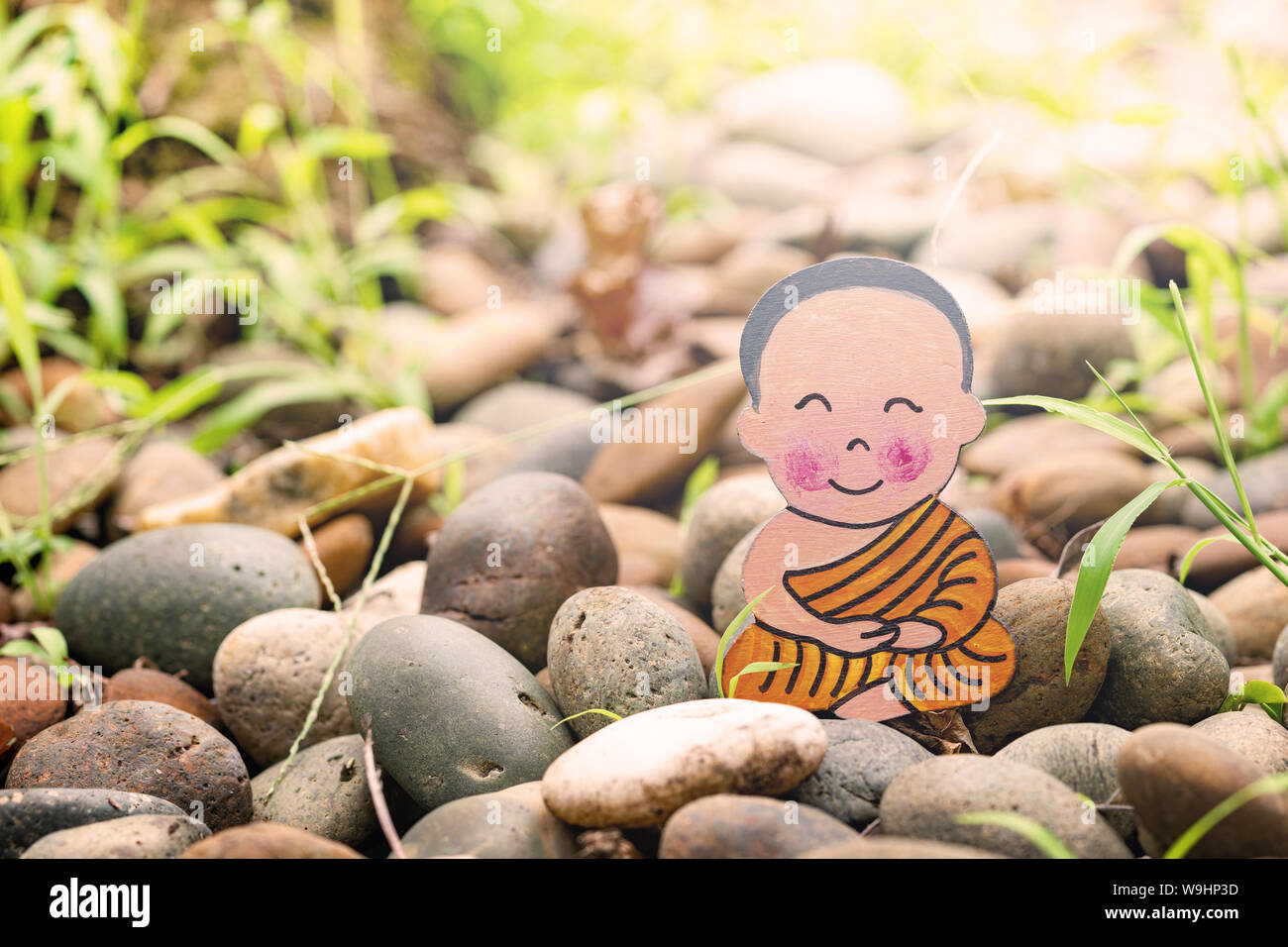 Little boy Buddhist, little Buddha, sitting on the sand on stones and ...