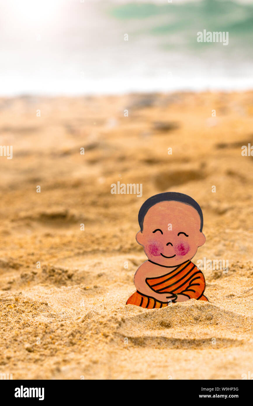 Little boy Buddhist, little Buddha, sitting on the sand on the beach ...