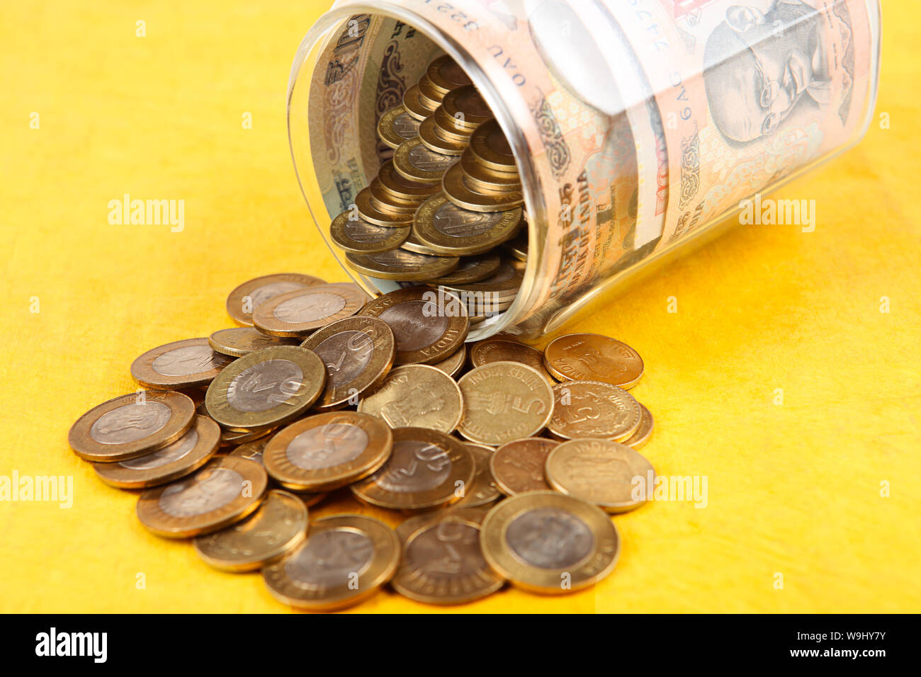 Jar spilling coins Stock Photo - Alamy