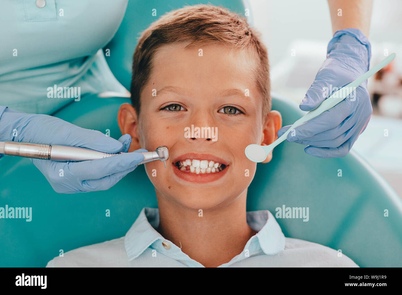 Cute boy smiling while teeth exam . Happy boy sitting in dentists chair ...