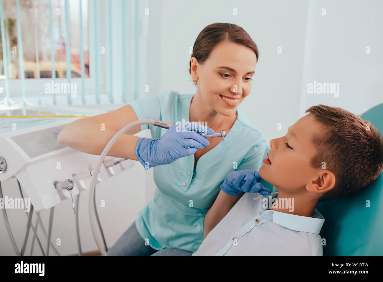 Cute boy smiling while teeth exam . Happy boy sitting in dentists chair ...