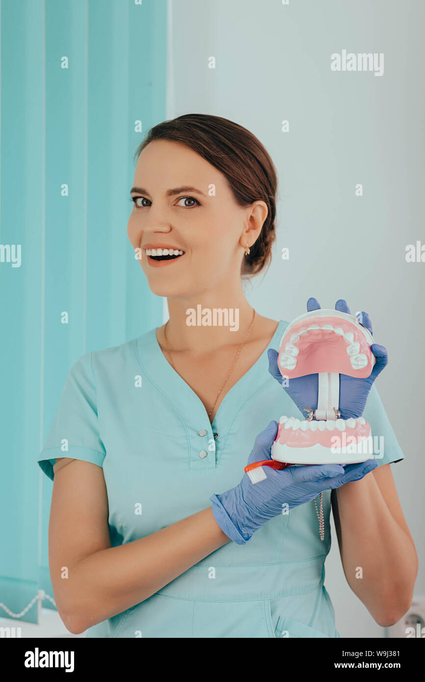 Portrait of shocked dentist woman looking at camera, holding tooth ...