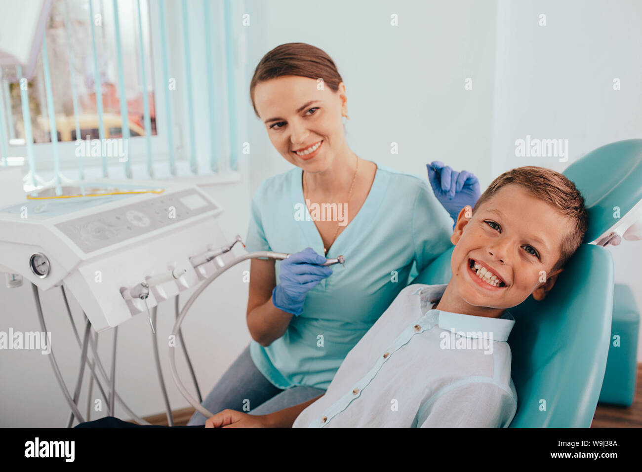 Cute boy smiling while teeth exam . Happy boy sitting in dentists chair ...