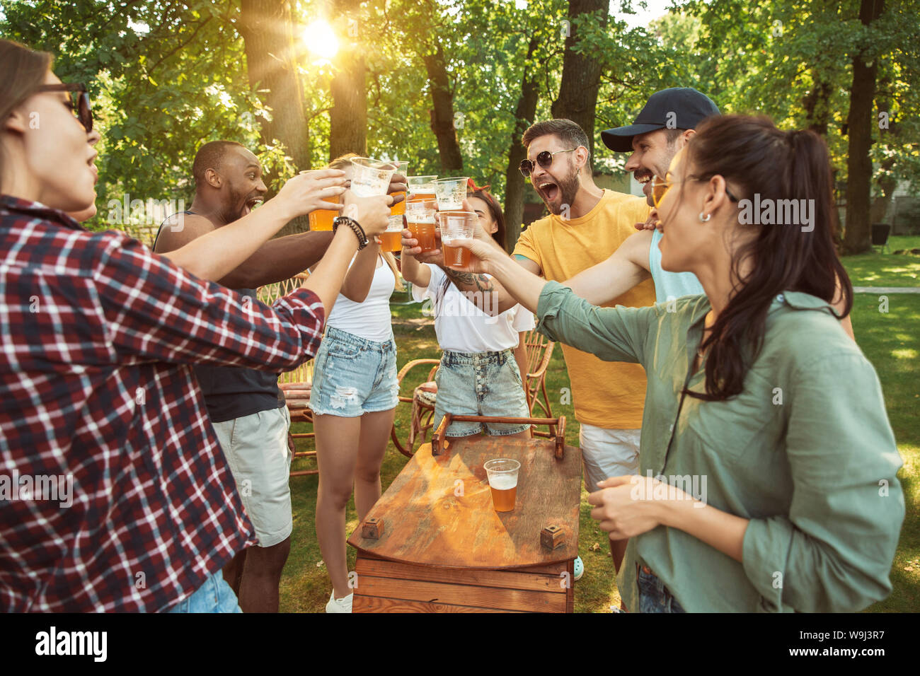 Group of happy friends having beer and barbecue party at sunny day ...