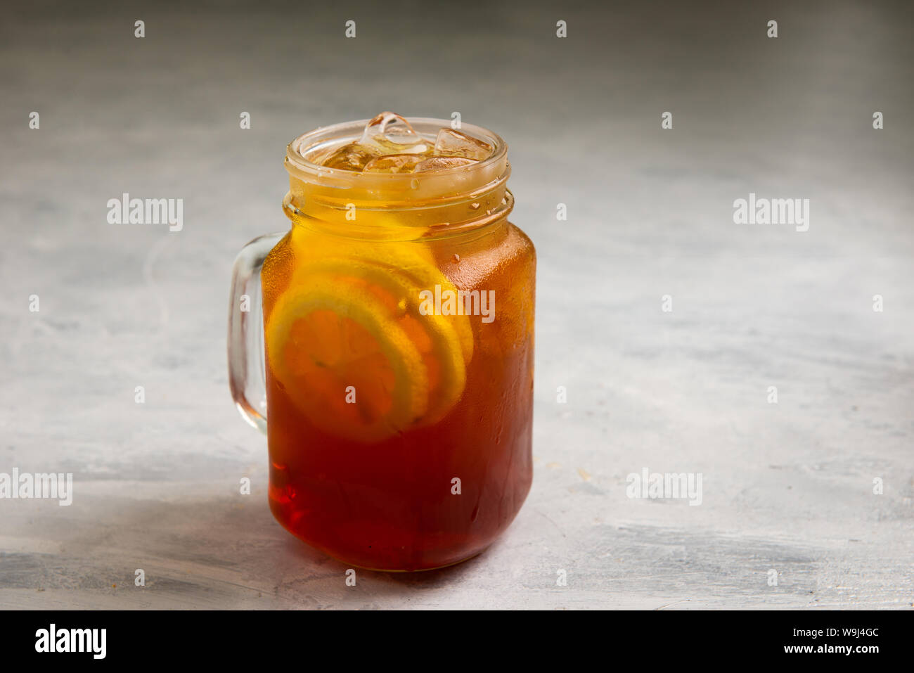 Iced tea with lemon slices and grey background Stock Photo - Alamy