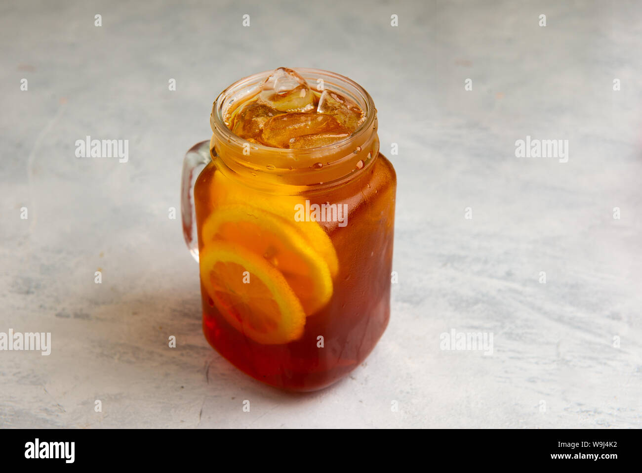 Iced tea with lemon slices and grey background Stock Photo - Alamy
