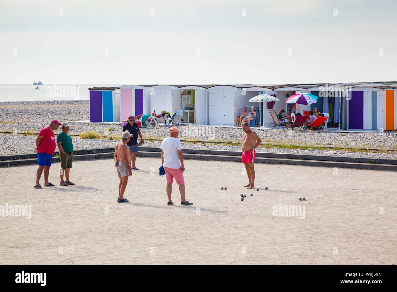 A group of people playing a game of boules or petanques on the beach on ...