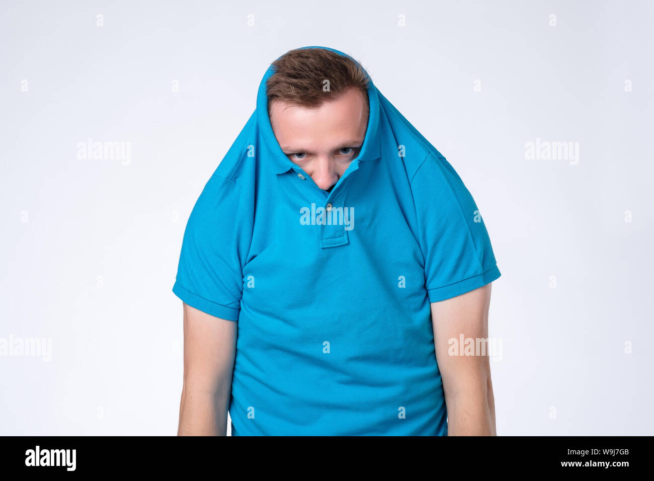 Young guy hiding his face in t-shirt being stressed Stock Photo - Alamy